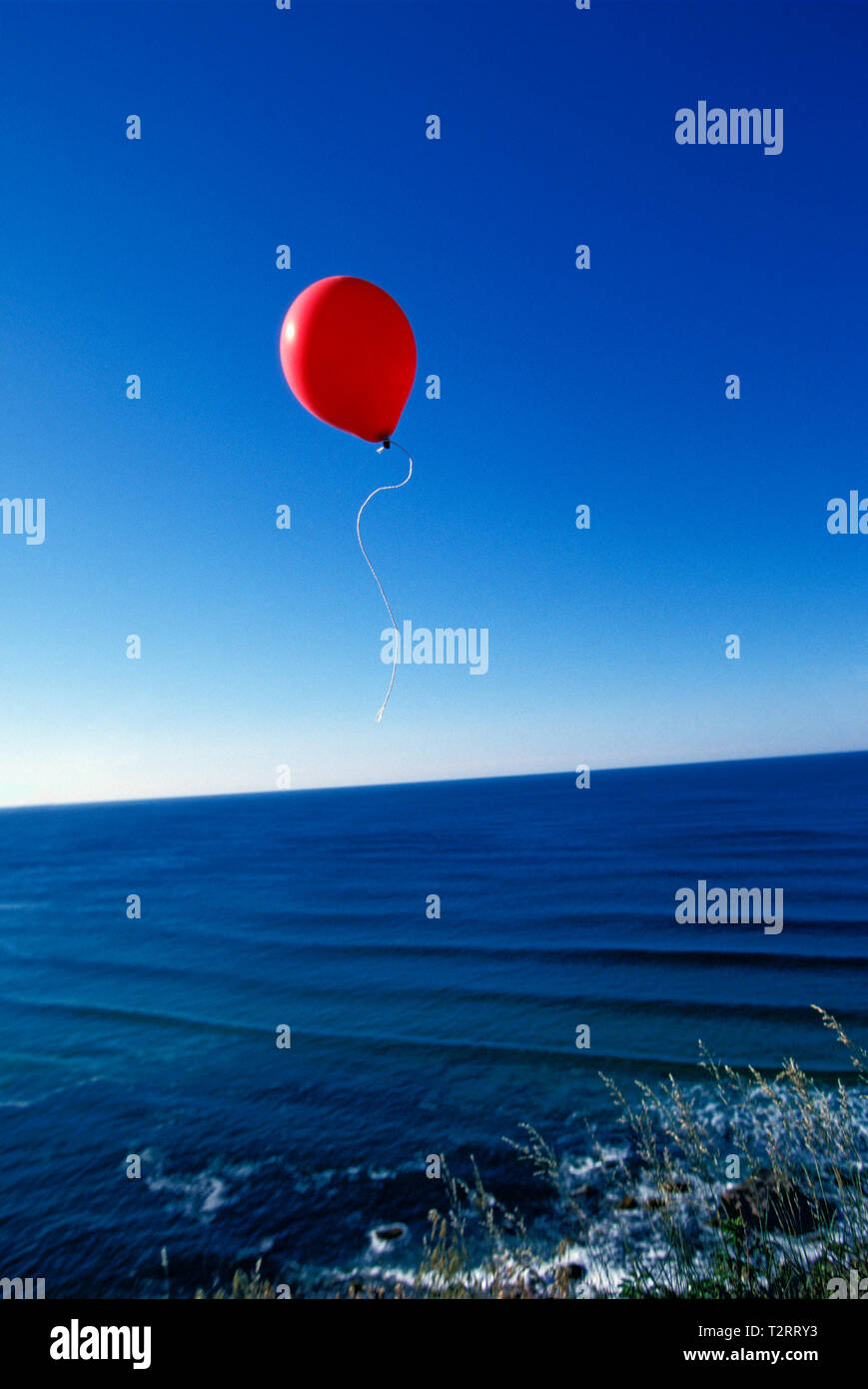 Red Balloon escapes and flies free over the Ocean Stock Photo - Alamy