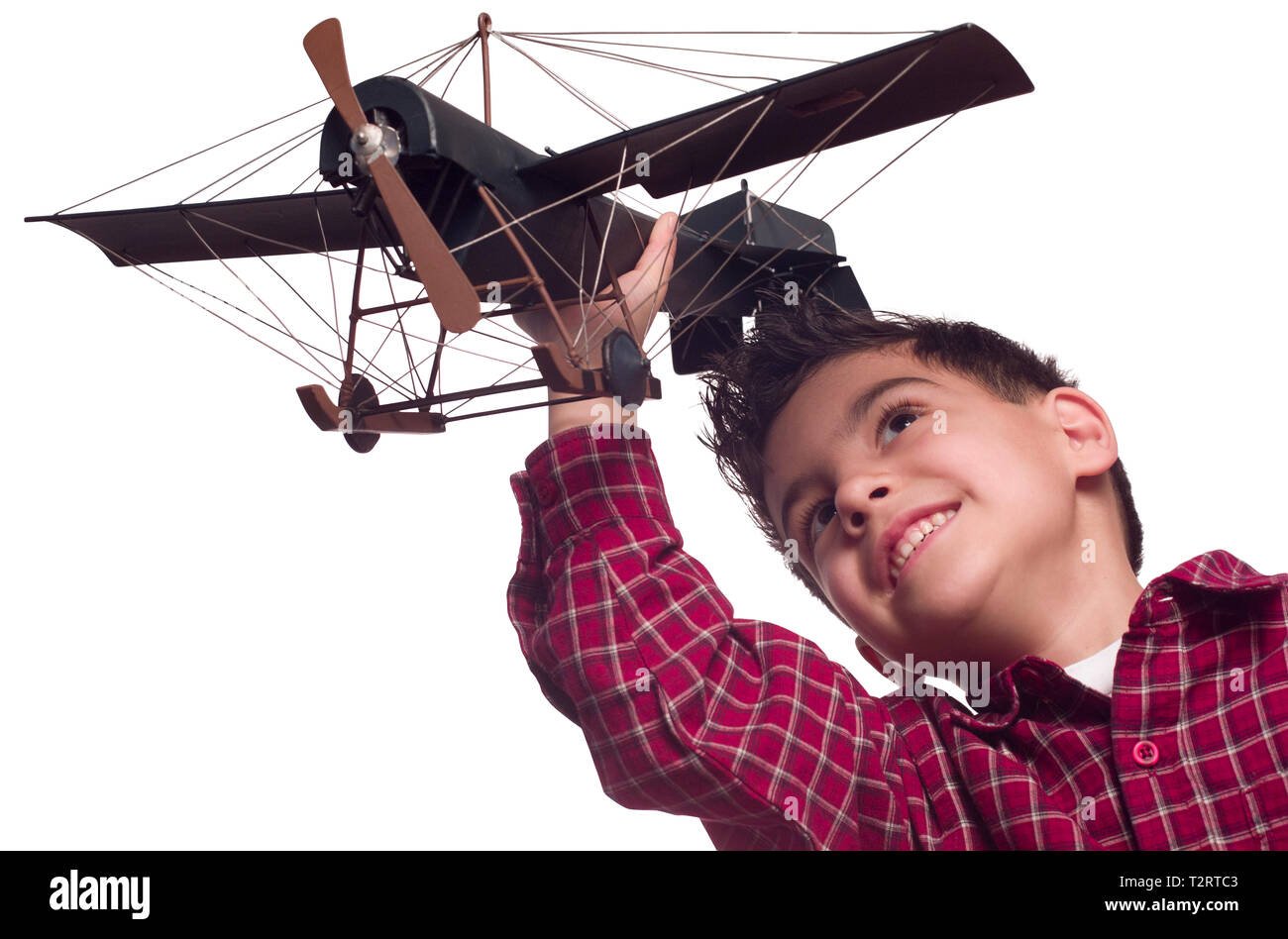 Small Latino boy pretending to fly a model plane on a white background ...