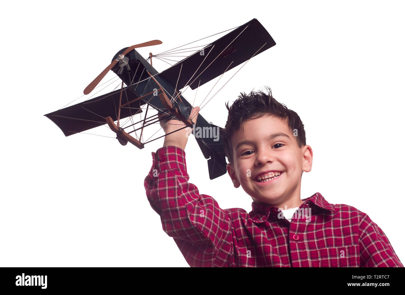 Small Latino boy pretending to fly a model plane on a white background ...
