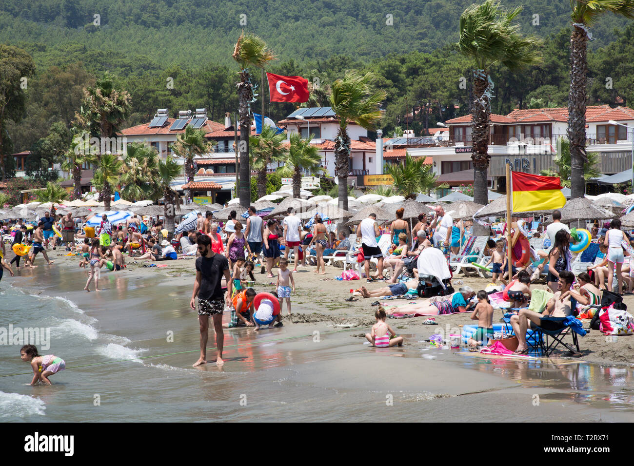 Tourists and locals enjoying the sun on the public beach, Akyaka, Mugla ...