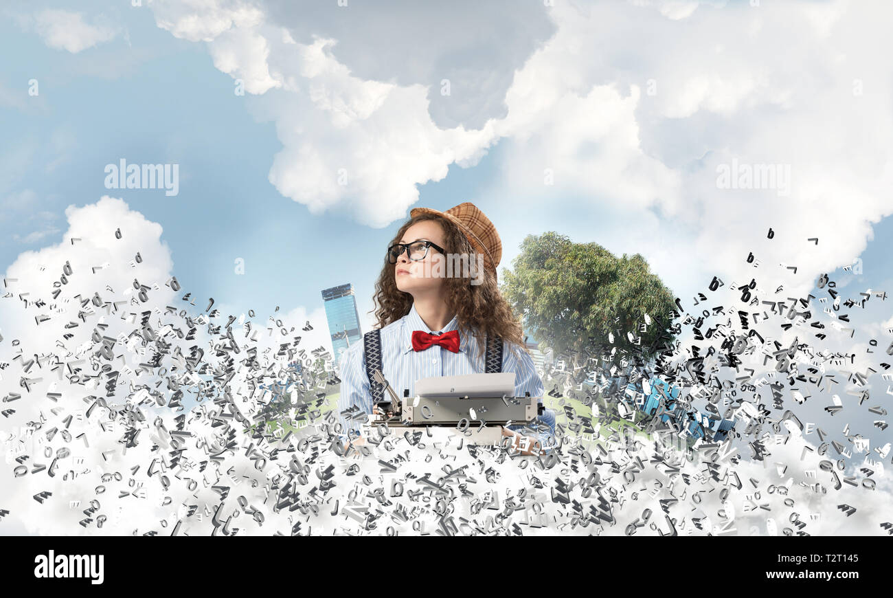 Young woman writer in hat and eyeglasses using typing machine while ...