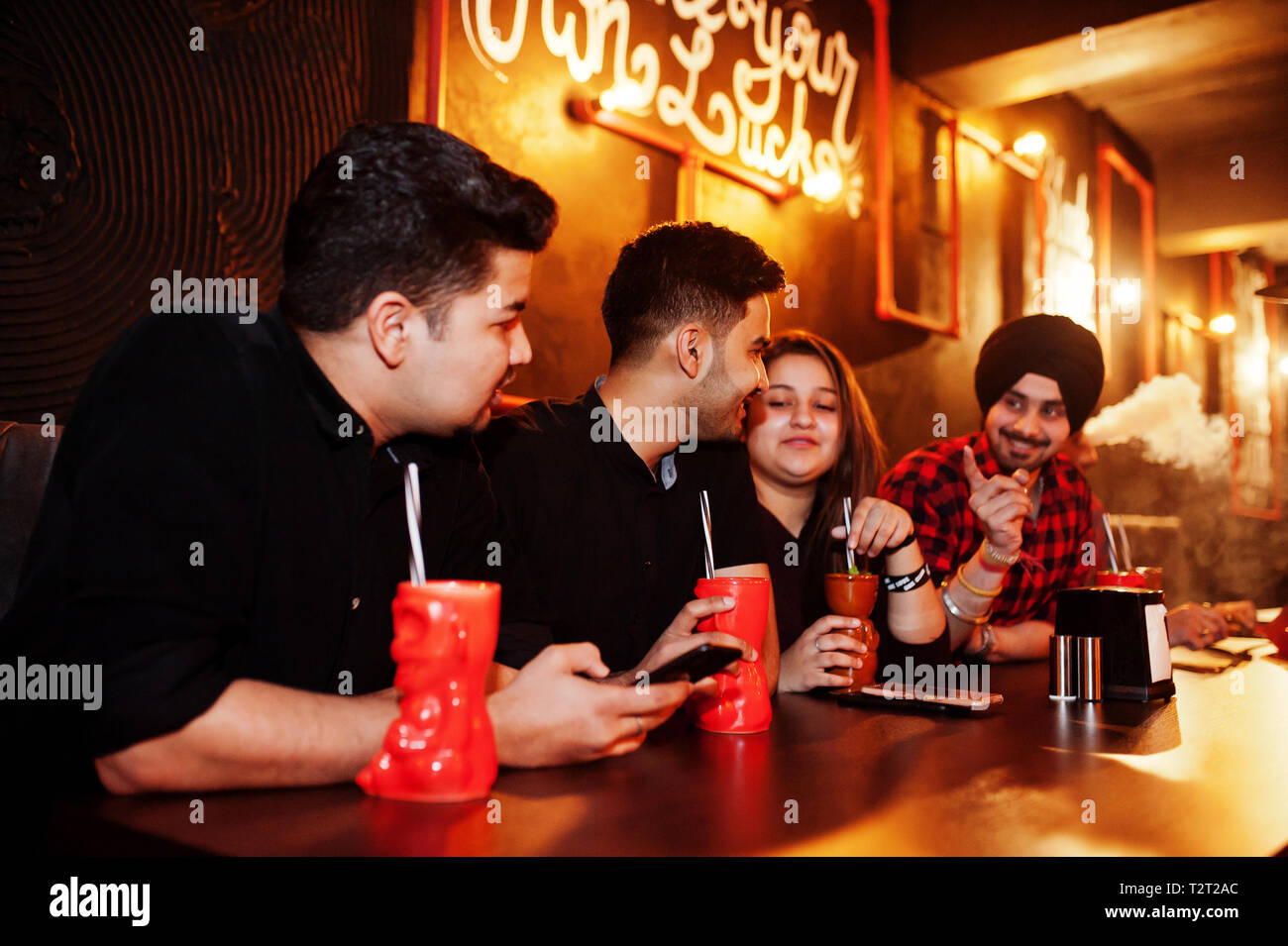 Group of indian friends having fun and rest at night club, drinking ...