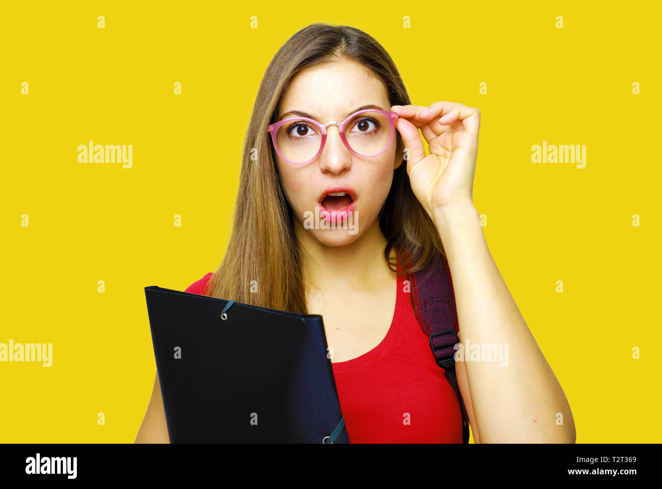 Surprised beautiful student girl. Young shocked student woman holding ...