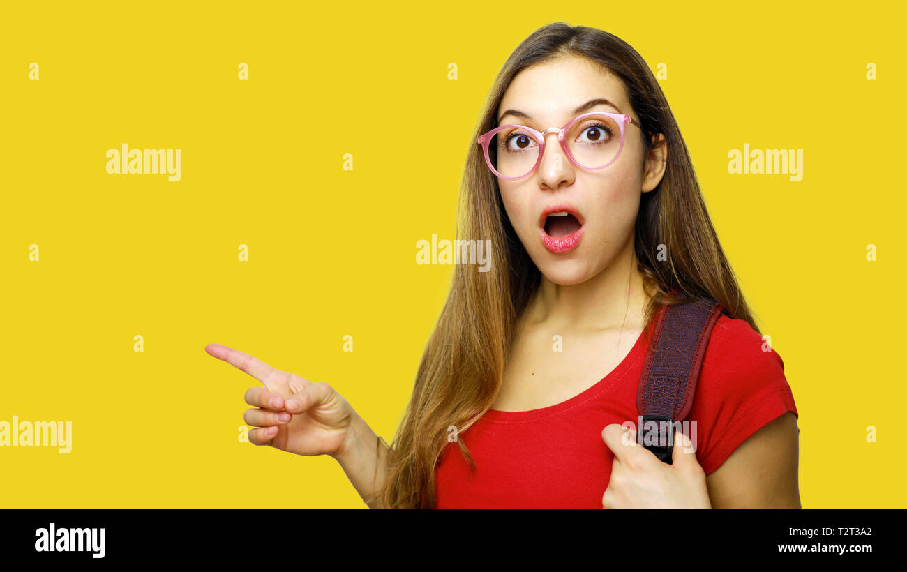 Astonished student pointing finger copy space over yellow background ...