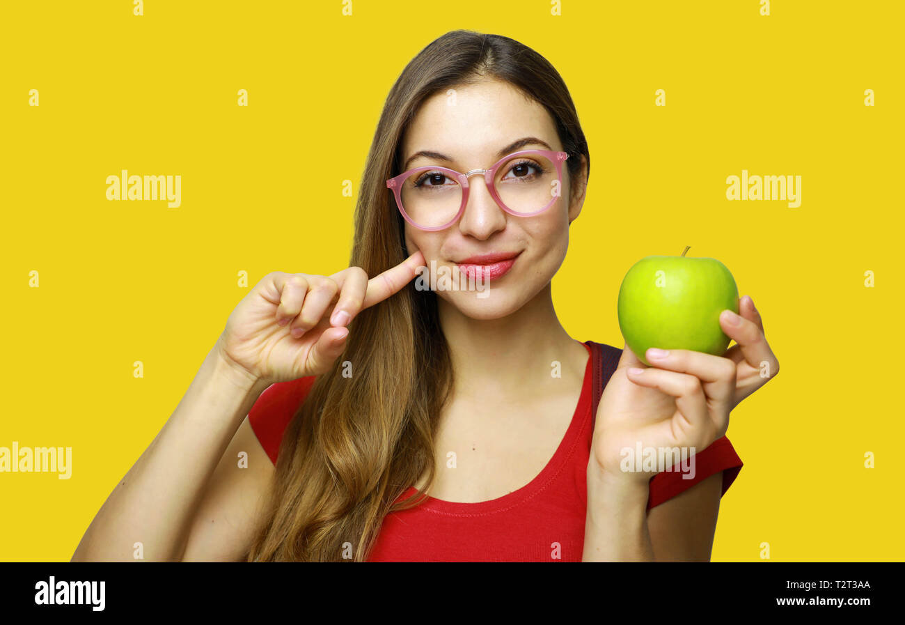Portrait of a smiling young school nerd girl holding an apple gesturing ...