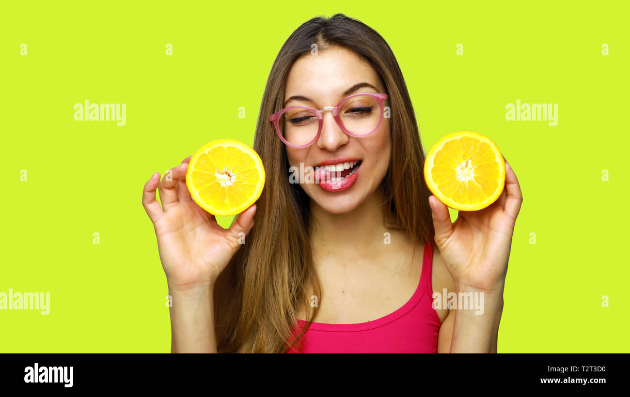 Funny girl holding two half orange on yellow background Stock Photo - Alamy