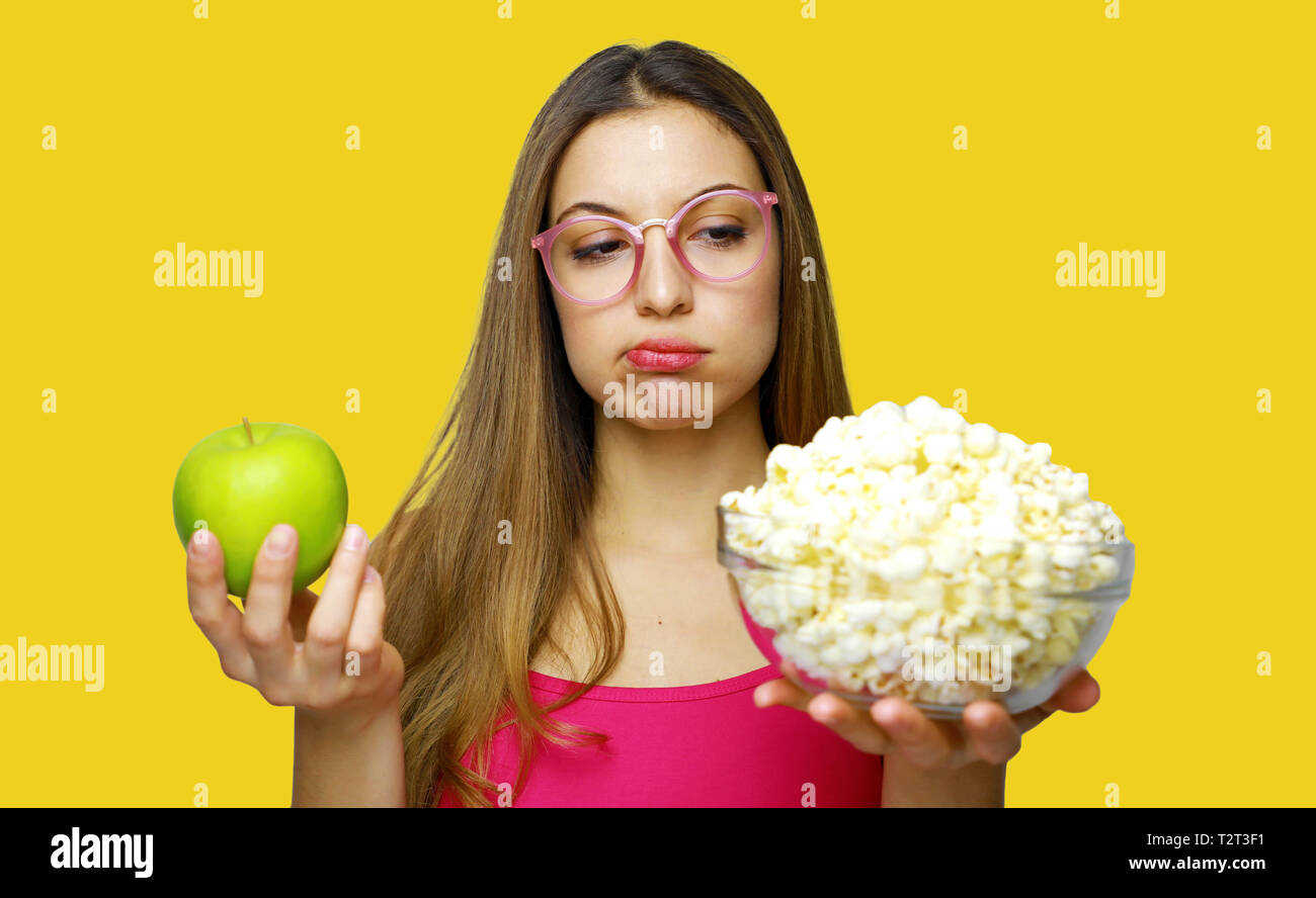 Woman choosing between unhealthy bowl of pop corn and an healthy green ...
