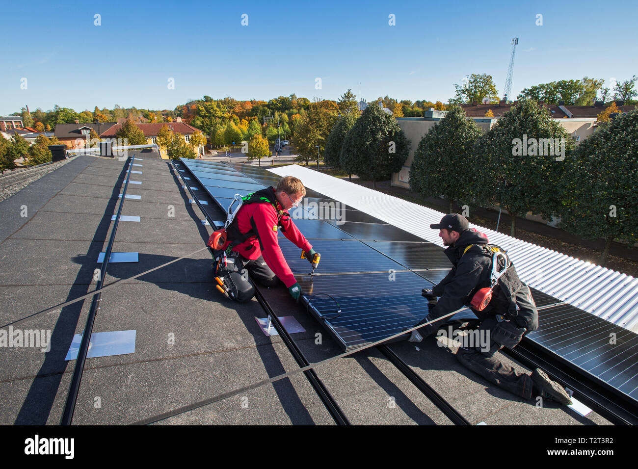 Handyman, with safety harness and safety line, assembles solar cells on ...