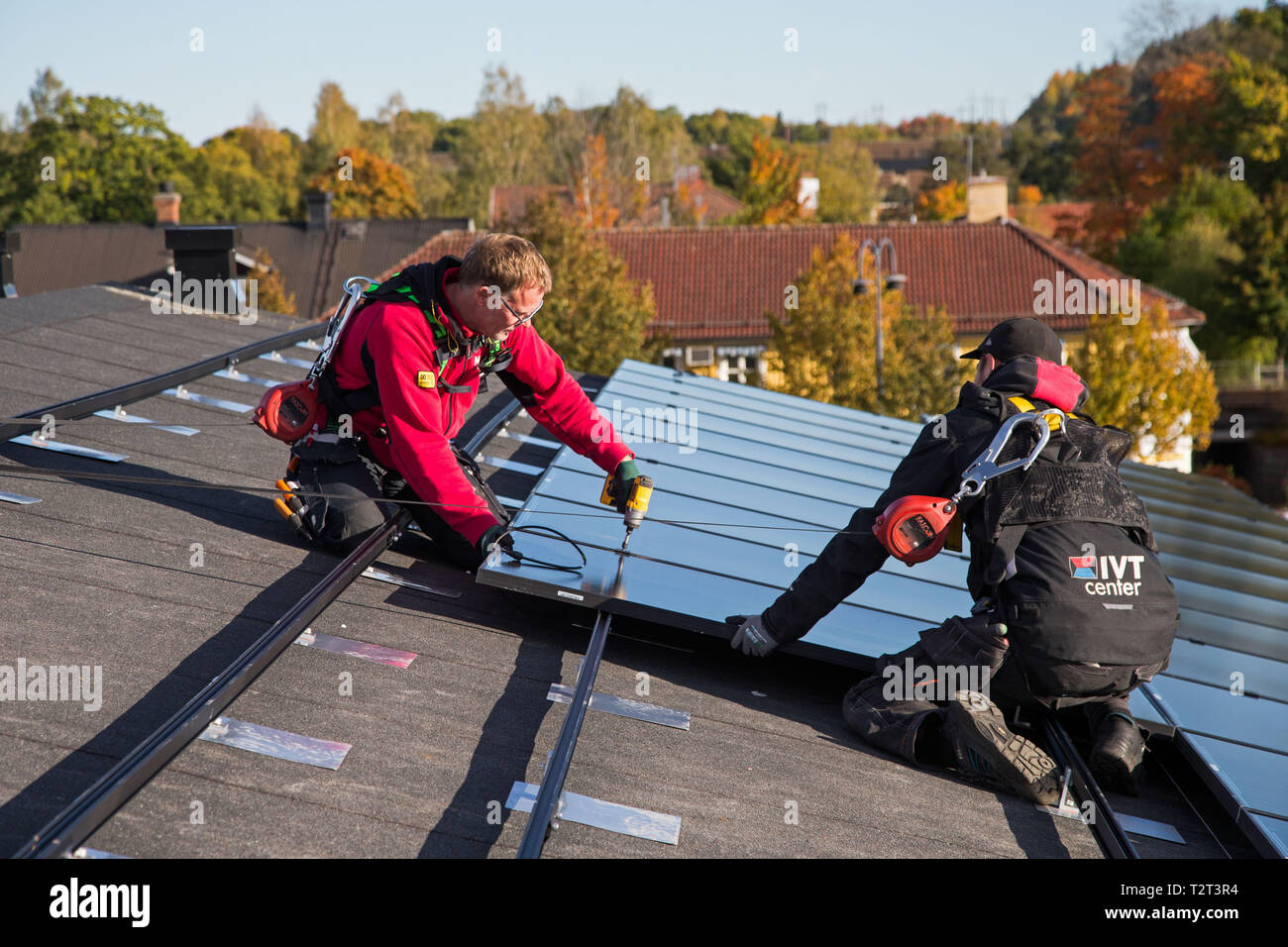 Handyman, with safety harness and safety line, assembles solar cells on ...