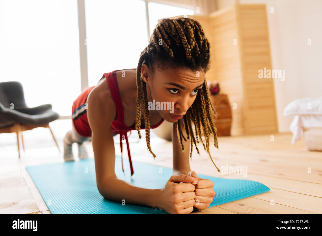 Exhausting plank. Dark-eyed woman with nice braids feeling exhausted ...