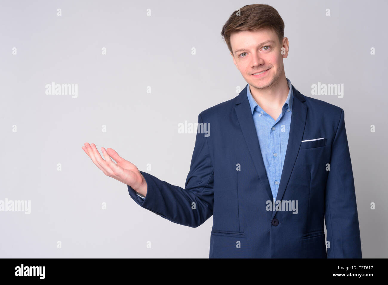 Studio shot of young handsome businessman wearing suit against white ...
