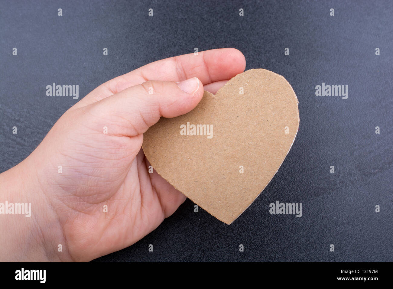 Heart shaped object in hand on a wooden black background Stock Photo ...
