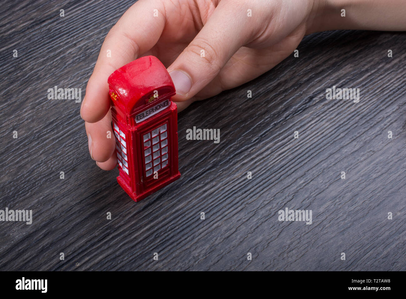 Hand holding a phone booth on a brown background Stock Photo - Alamy