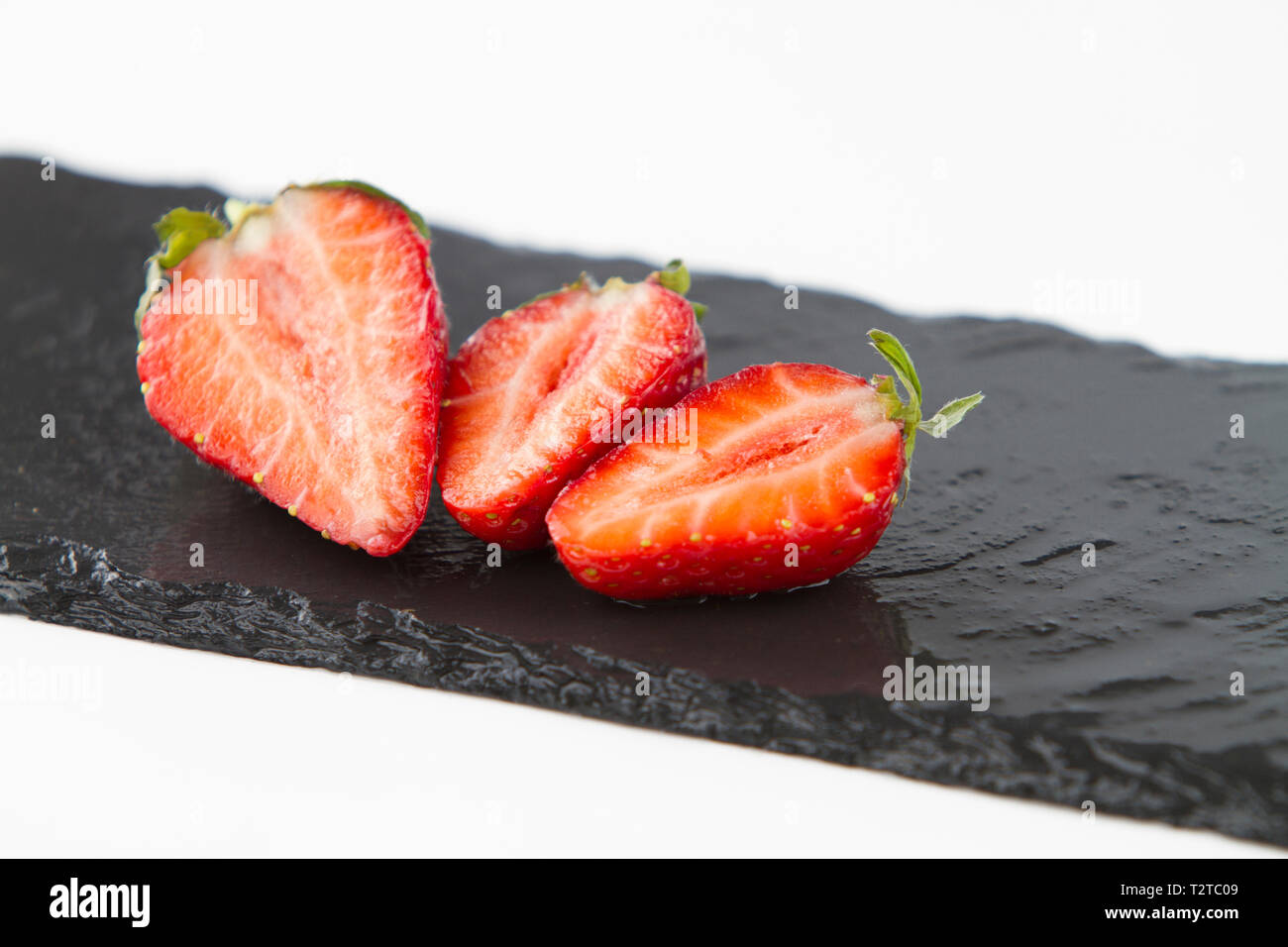 Close-up of three isolated strawberries on a rectangular strip of ...