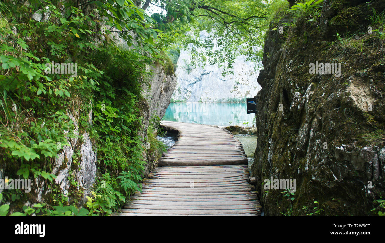 Wooden pathway over the water between rocks, Plitvice Lakes in Croatia ...