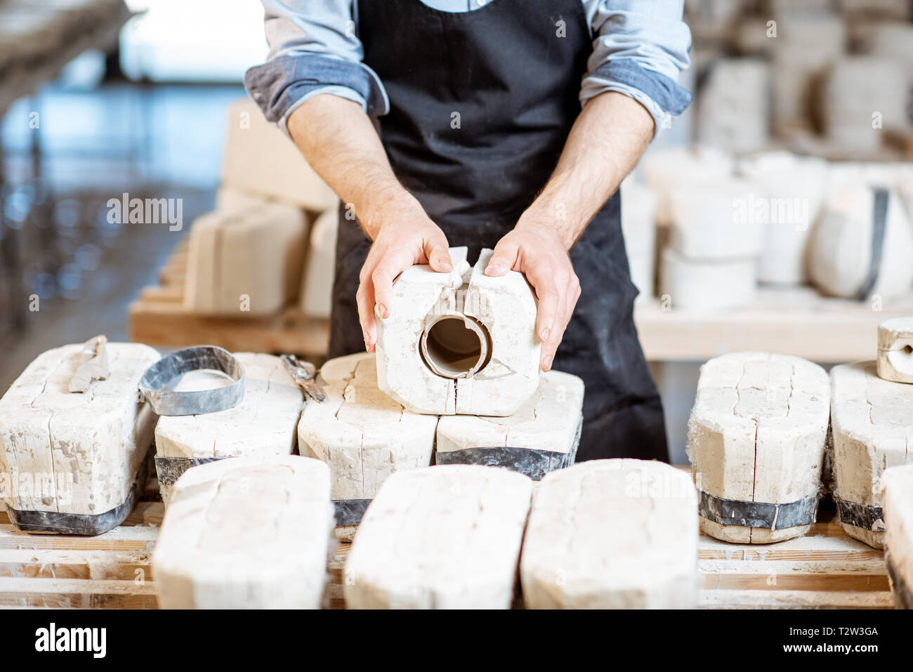 Male worker getting clay products from the gypsum forms at the pottery ...