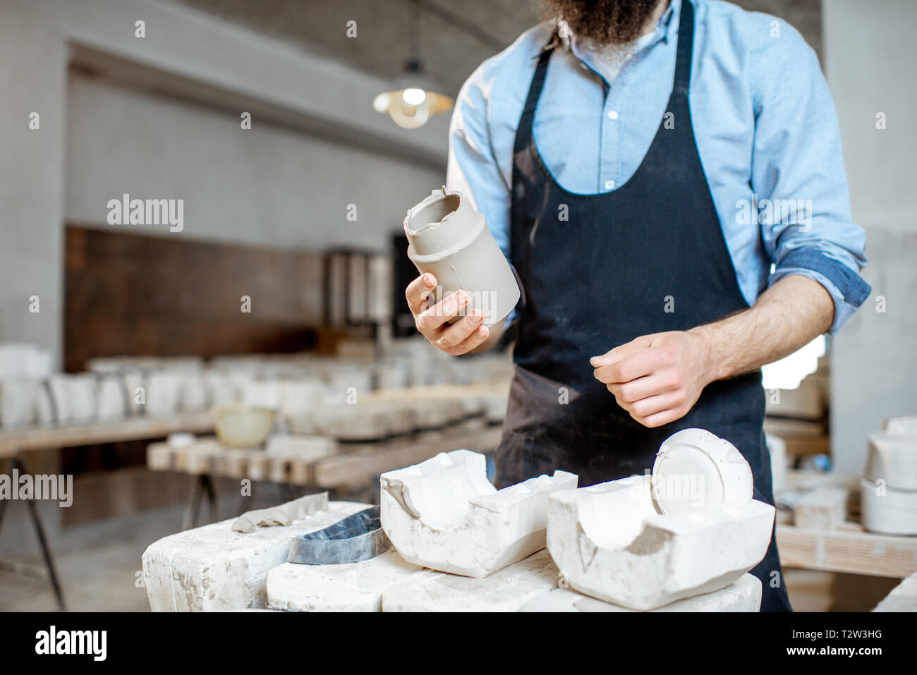 Male worker getting clay products from the gypsum forms at the pottery ...