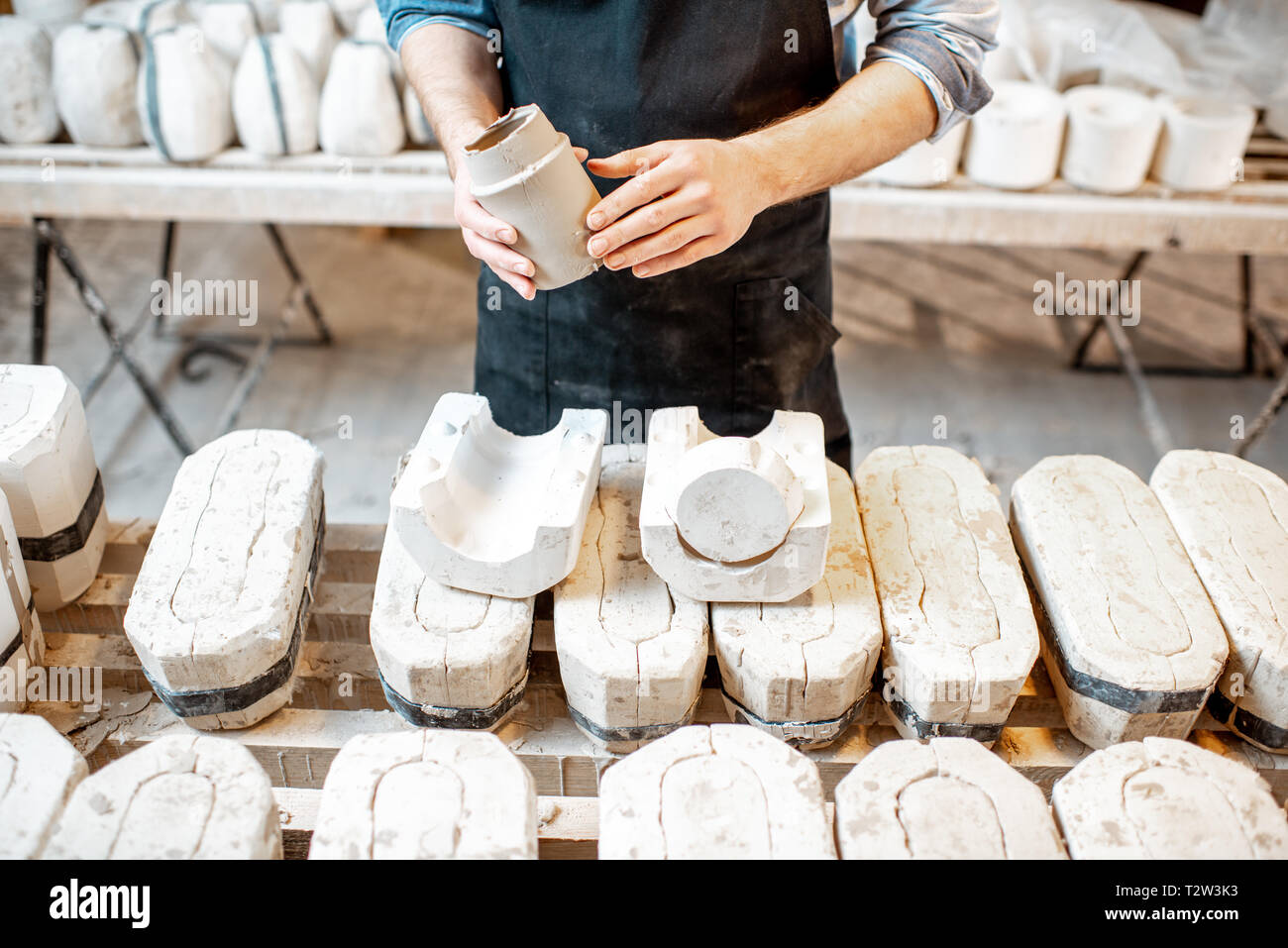 Male worker getting clay products from the gypsum forms at the pottery ...