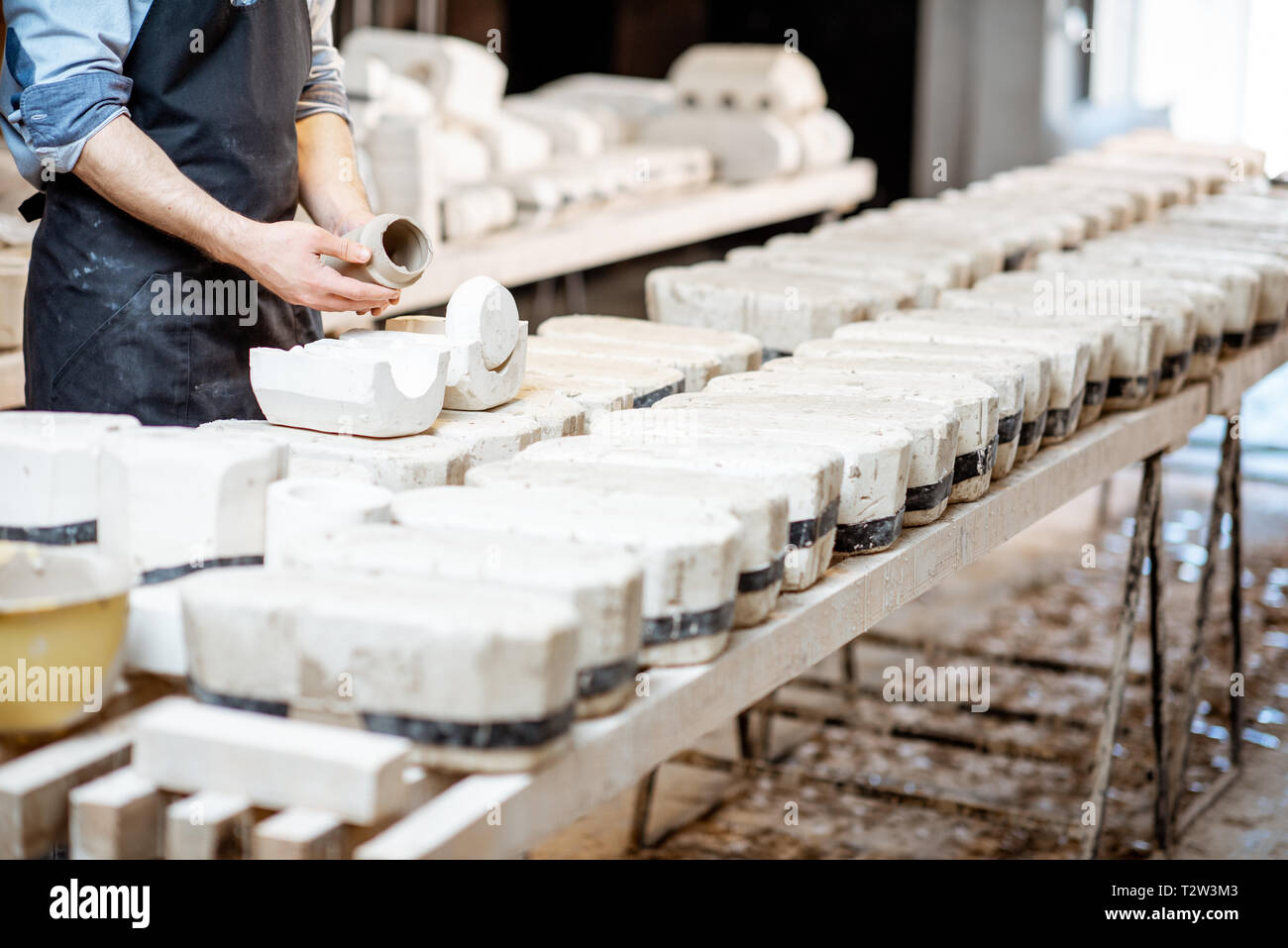 Male worker getting clay products from the gypsum forms at the pottery ...