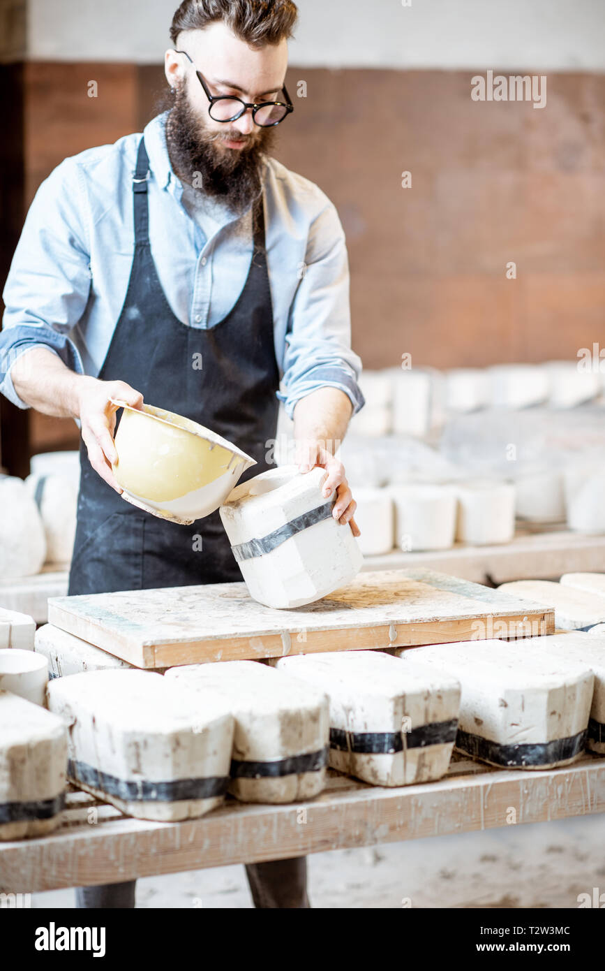 Handsome worker pouring special liquid into the gypsum form at the ...