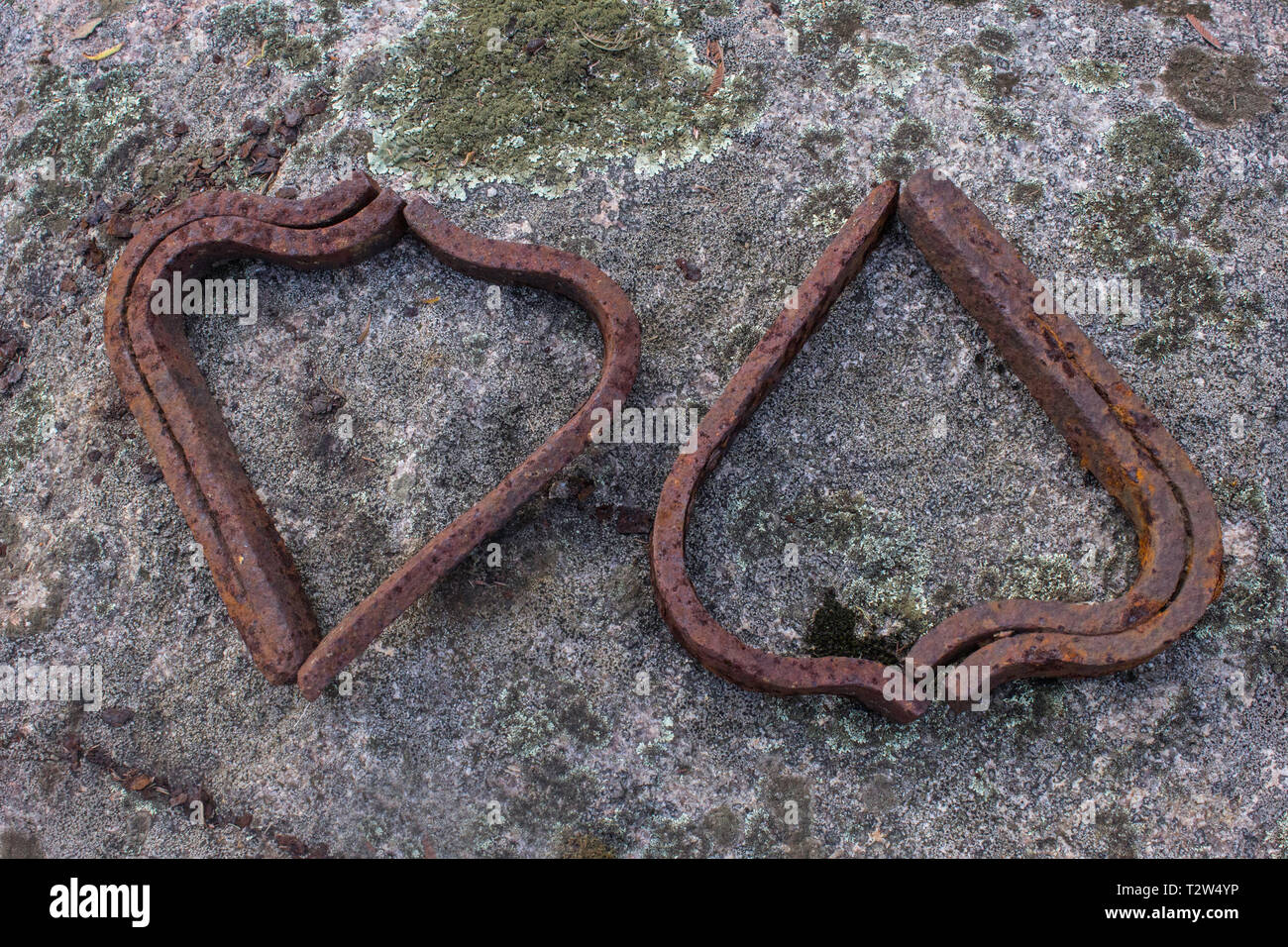 Old rusty railway spikes arranges to look like hearts on a rock with ...