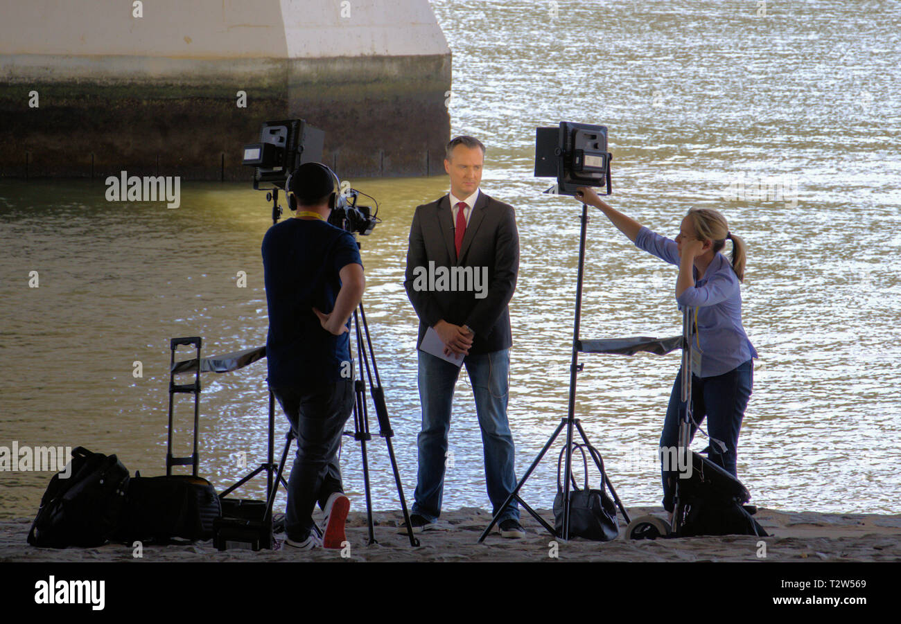A TV crew including a cameraman, lighting technician and presenter look ...