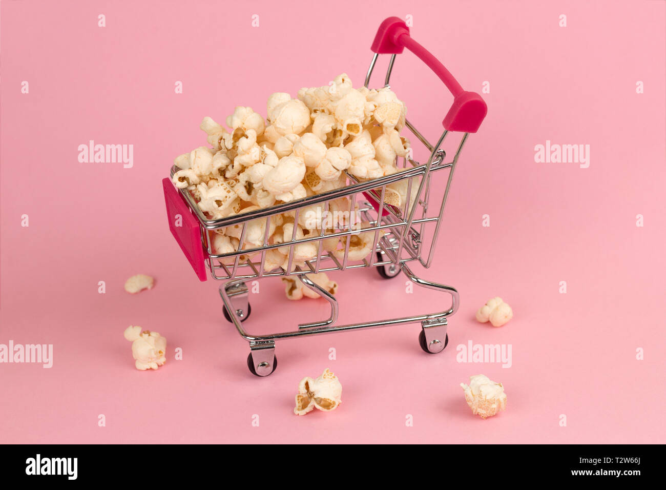 shopping cart full of popcorn on pink pastel background Stock Photo - Alamy
