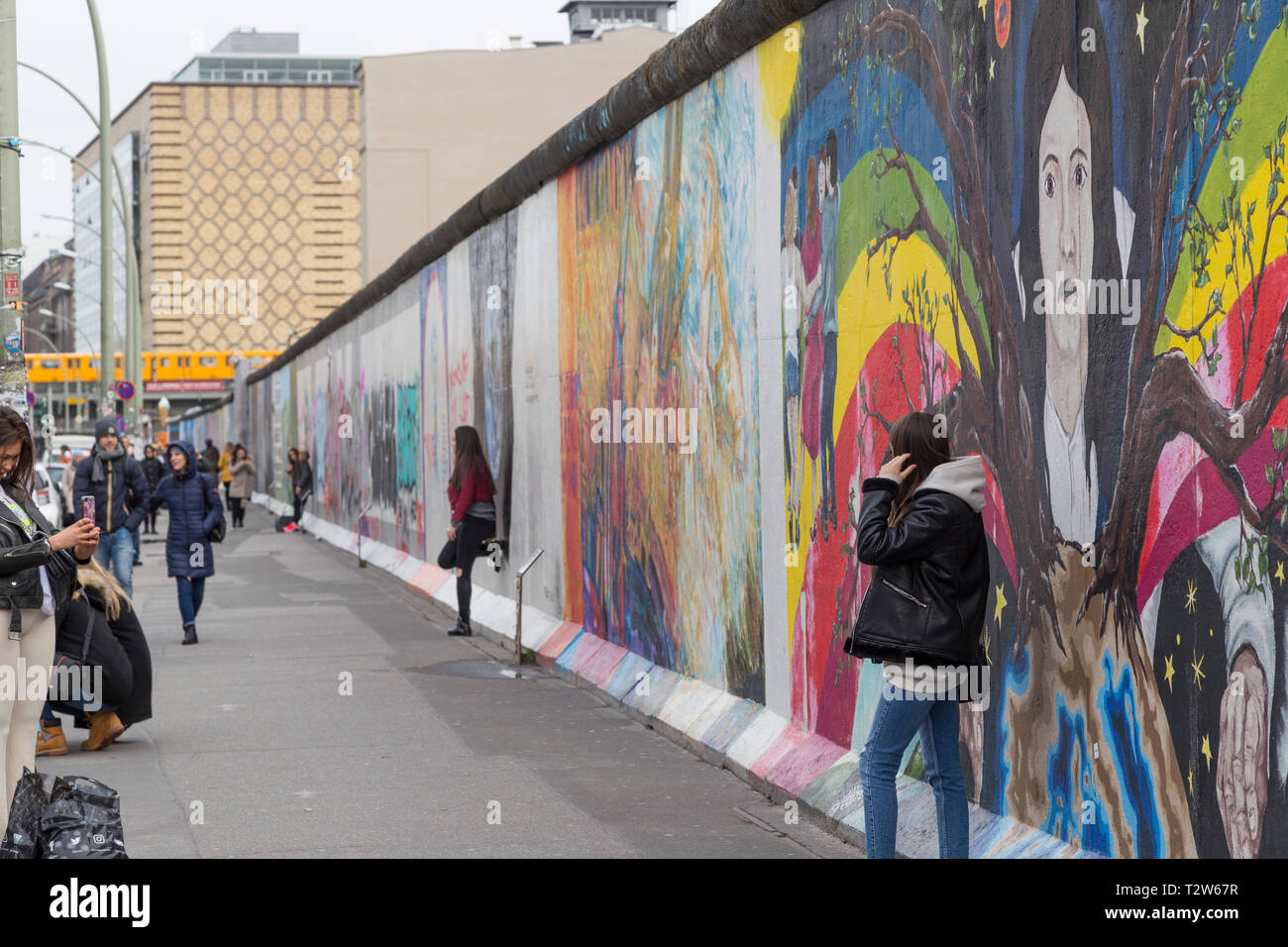 Tourists walking by, taking photos and posing in front of murals at the ...