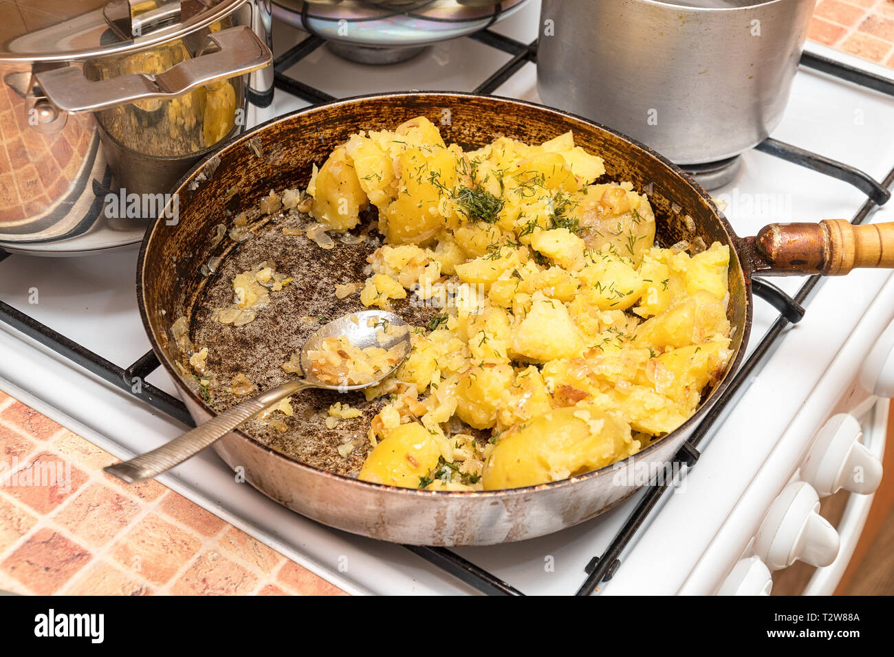 Fried potatoes with dill in a pan on a gas stove Stock Photo - Alamy