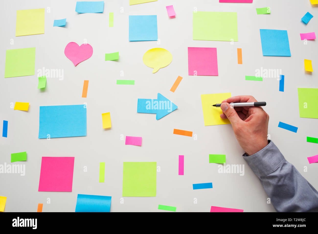 Caucasian businessman writing on a post it note surround by post it ...