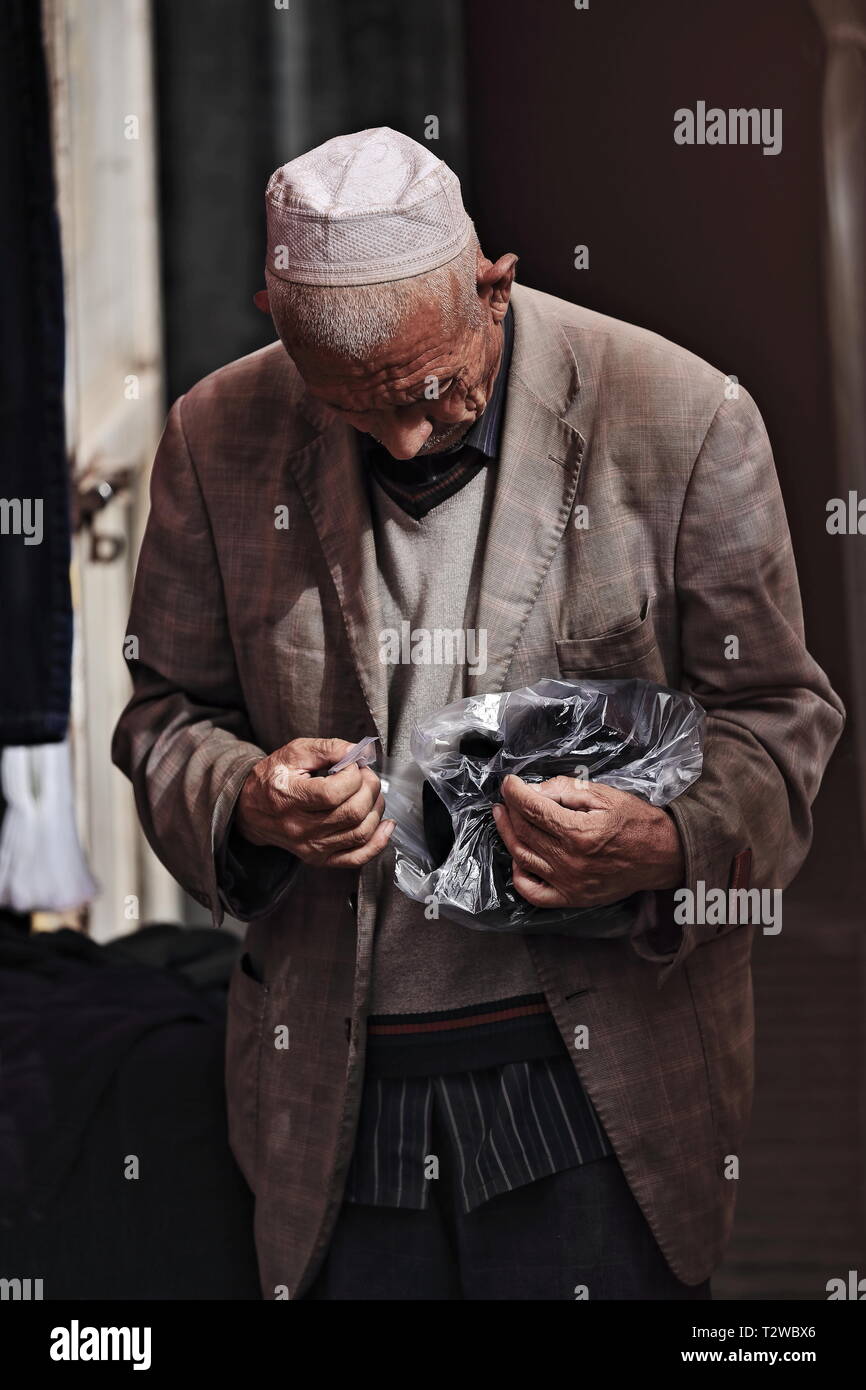 Bearded Uyghur man wearing doppa-skullcap at the city's bazaar. Hotan ...