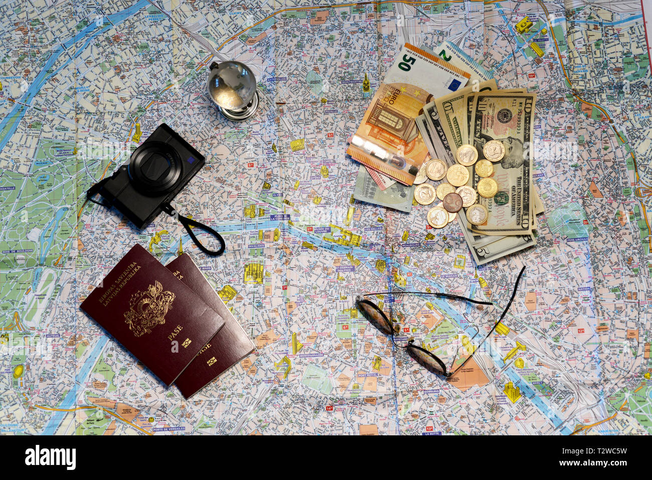 Sunglasses, a glass globe, passports, camera and money on a tourist map ...