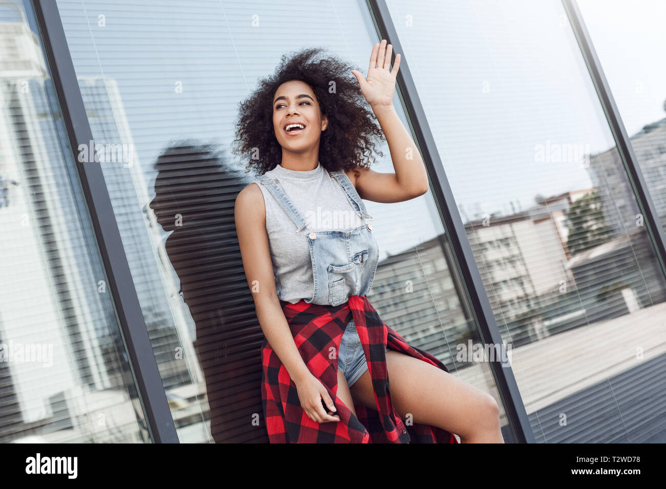 Young woman in the city street standing leaning on window waving to ...