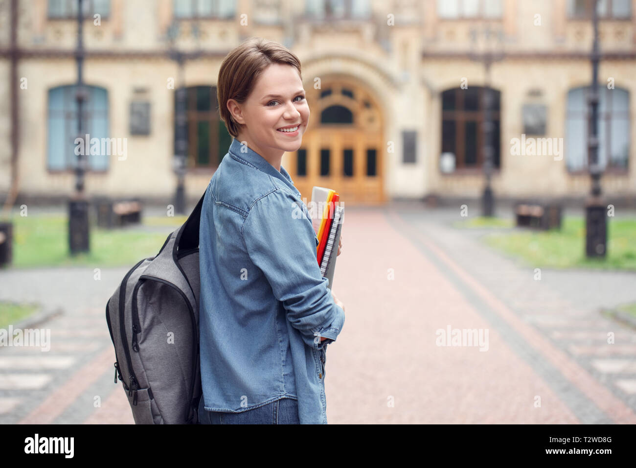 Young female student carrying backpack at university campus standing ...