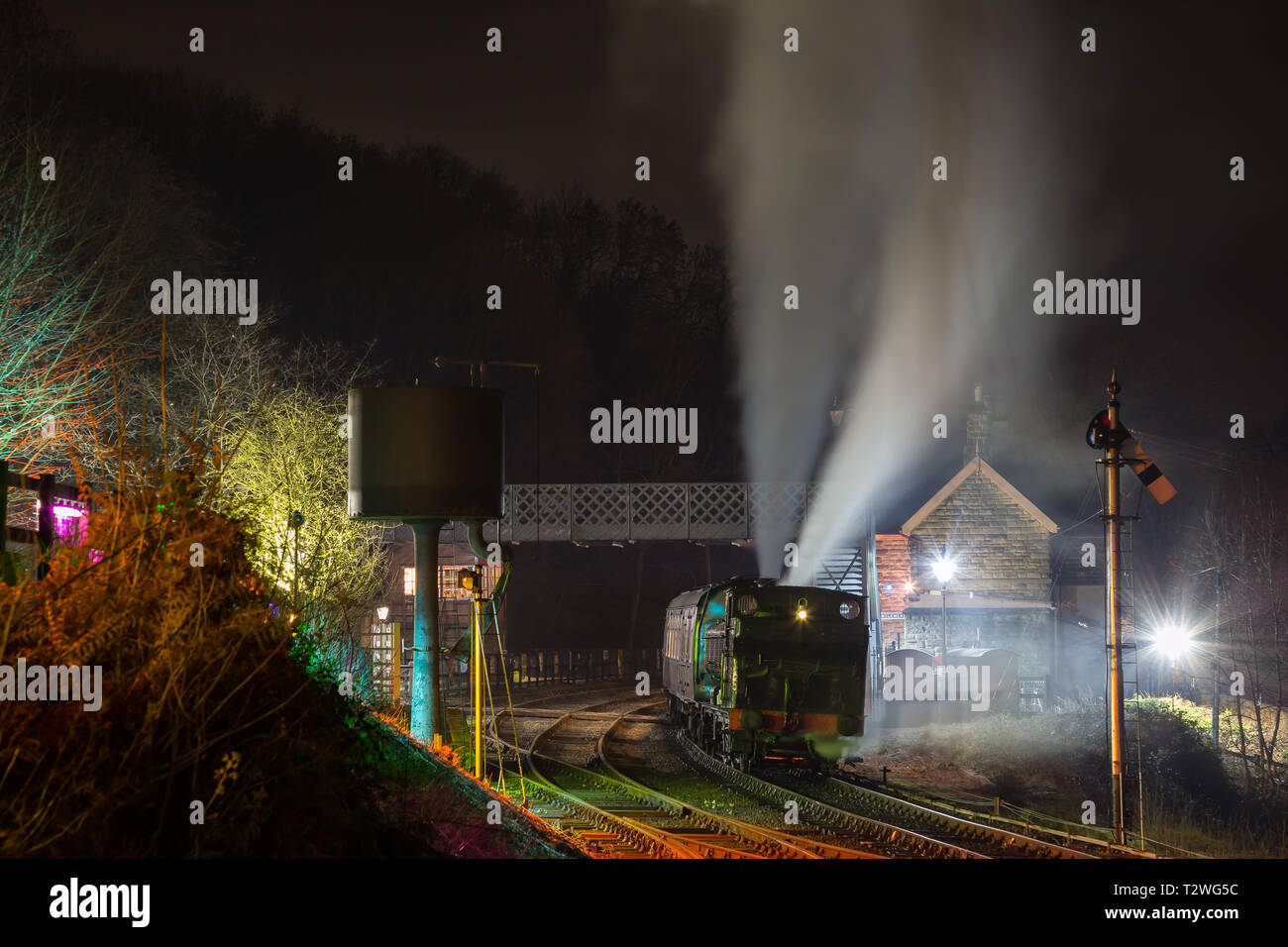 Atmospheric, night time view of vintage British steam train letting off ...