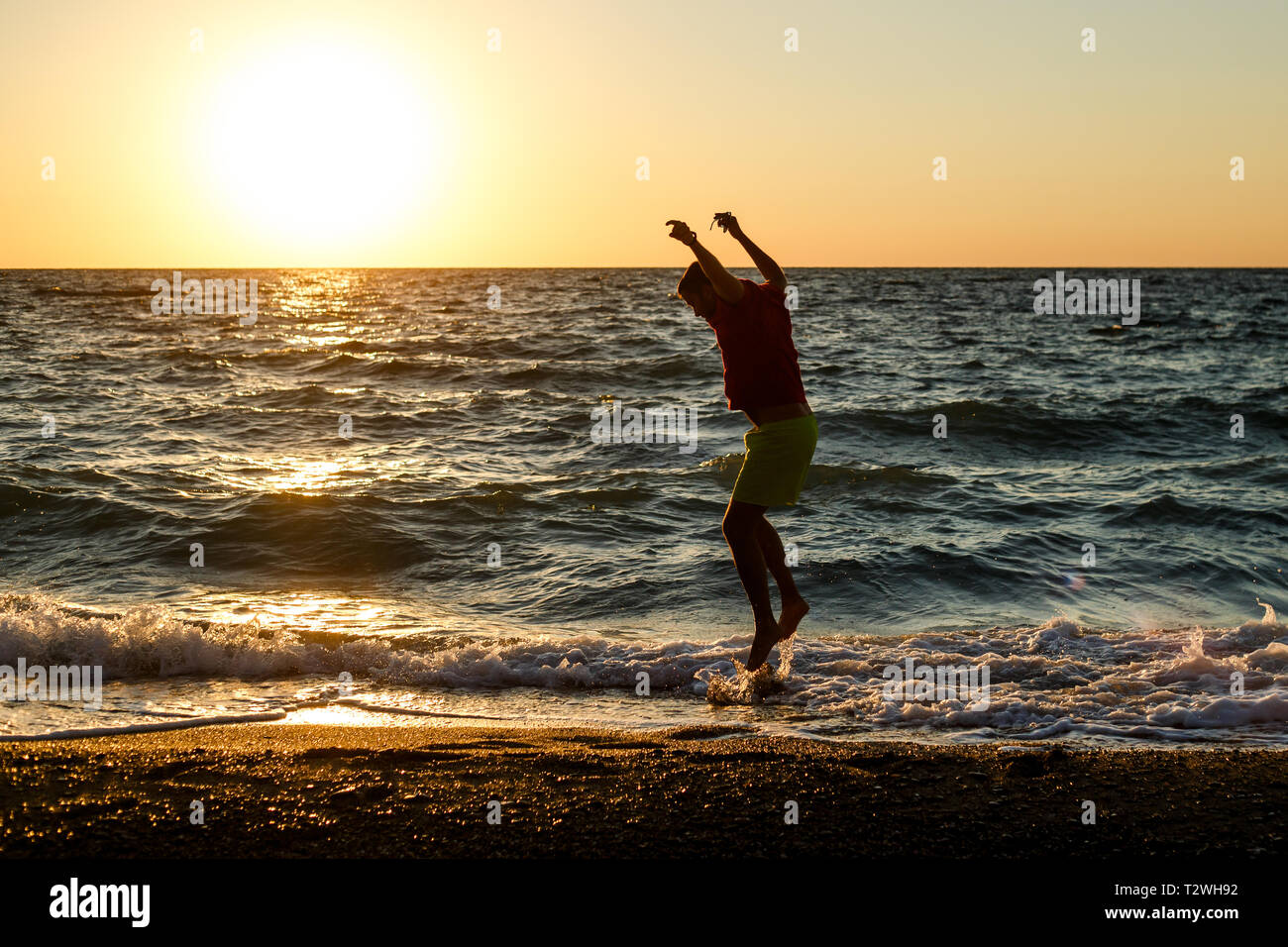 Photo of happy man jumping on seashore at sunset Stock Photo - Alamy