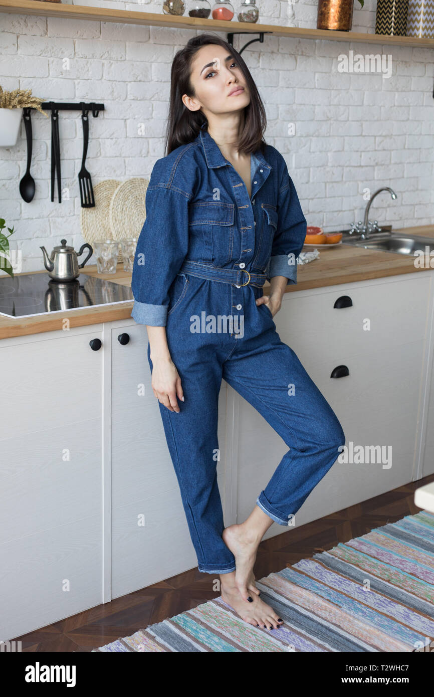 Beautiful woman in denim overalls standing in the kitchen Stock Photo ...