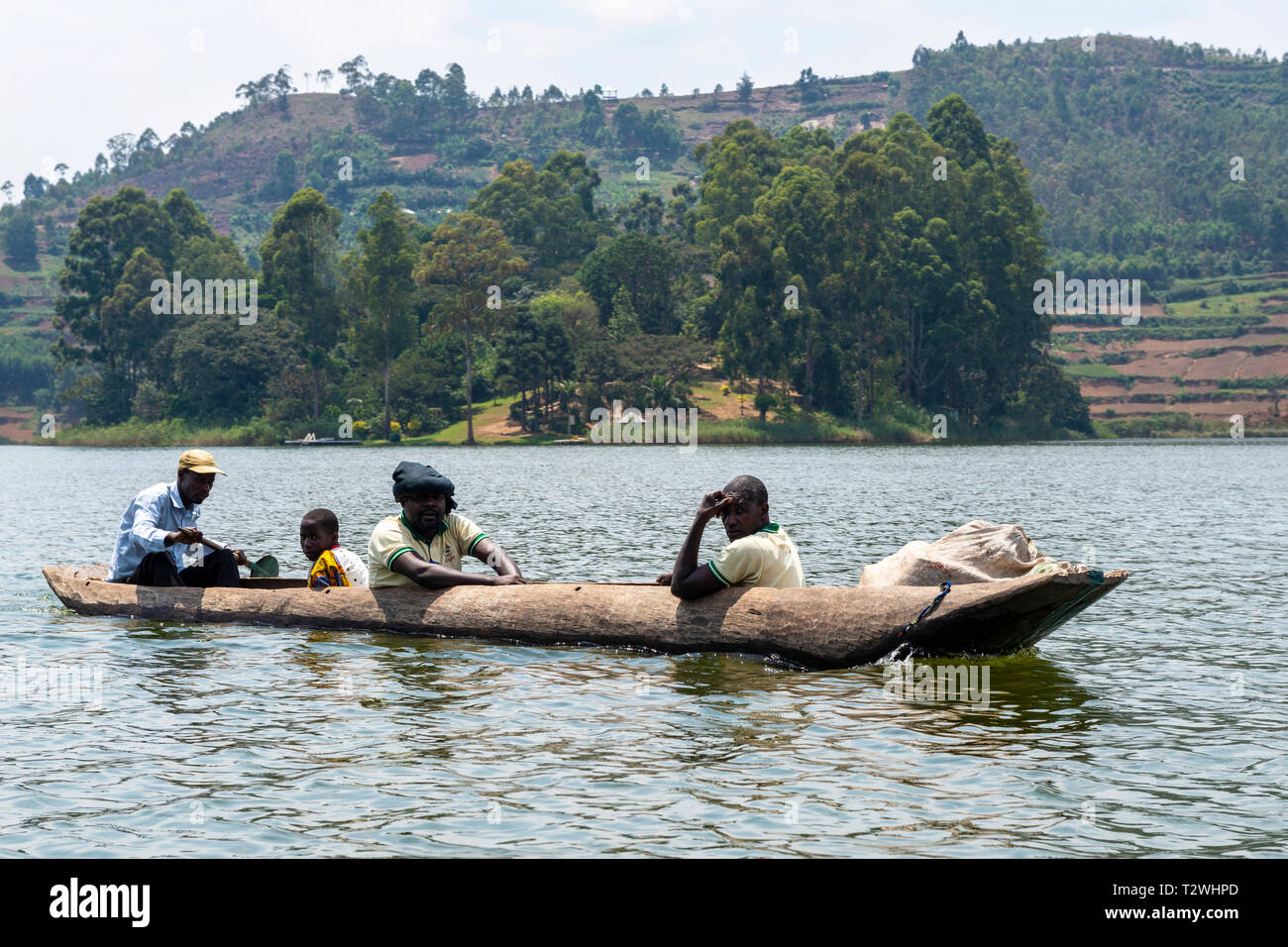 Boatman ferrying passengers in dugout canoe on Lake Bunyonyi in South ...