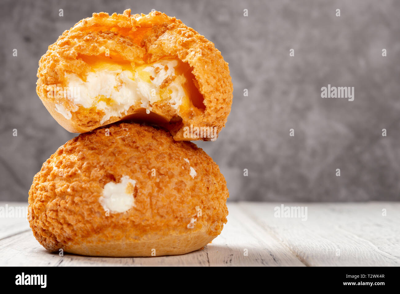 two pieces sweet puffs and one with a bite on a white wood table with ...