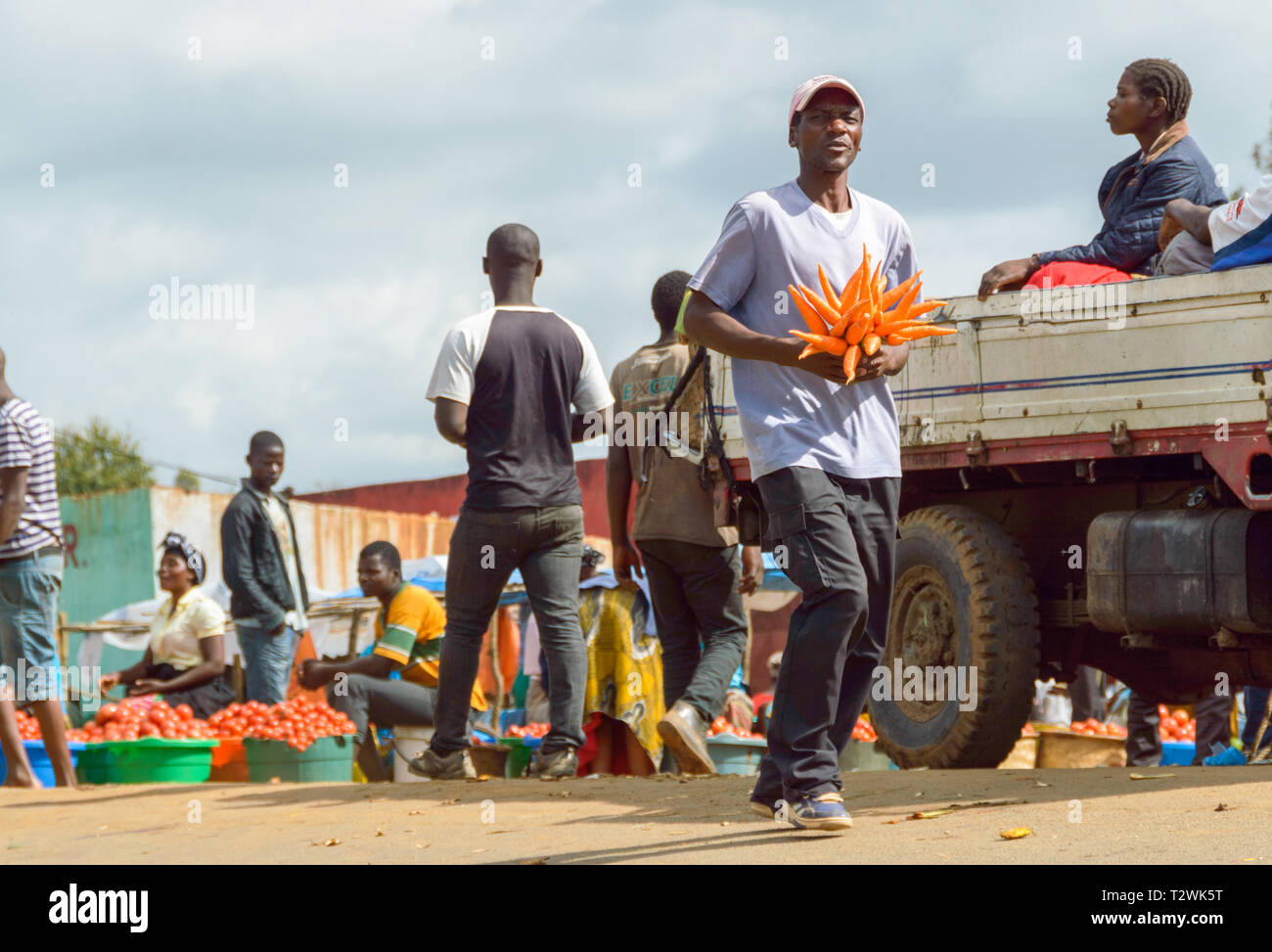 Malawian man selling carrots approaches a truck filled with women and ...