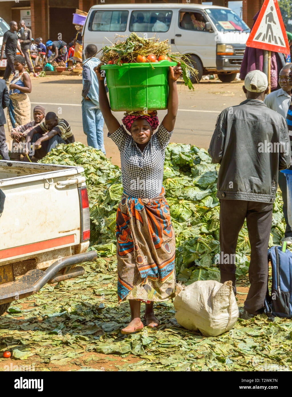 oman selling bucket of tomatoes carried on her head in road side market ...