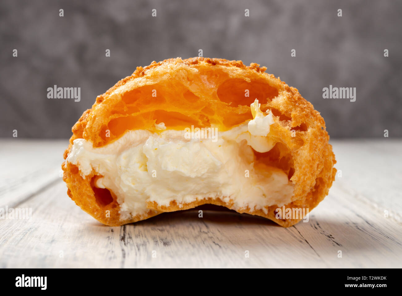 sweet puff with a bite on a white wood table Stock Photo - Alamy