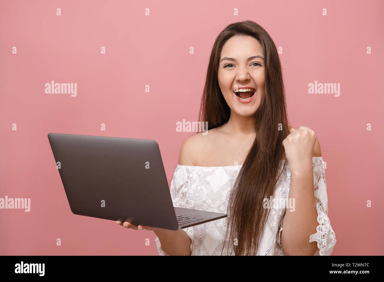 emotional young woman with laptop on pink background Stock Photo - Alamy