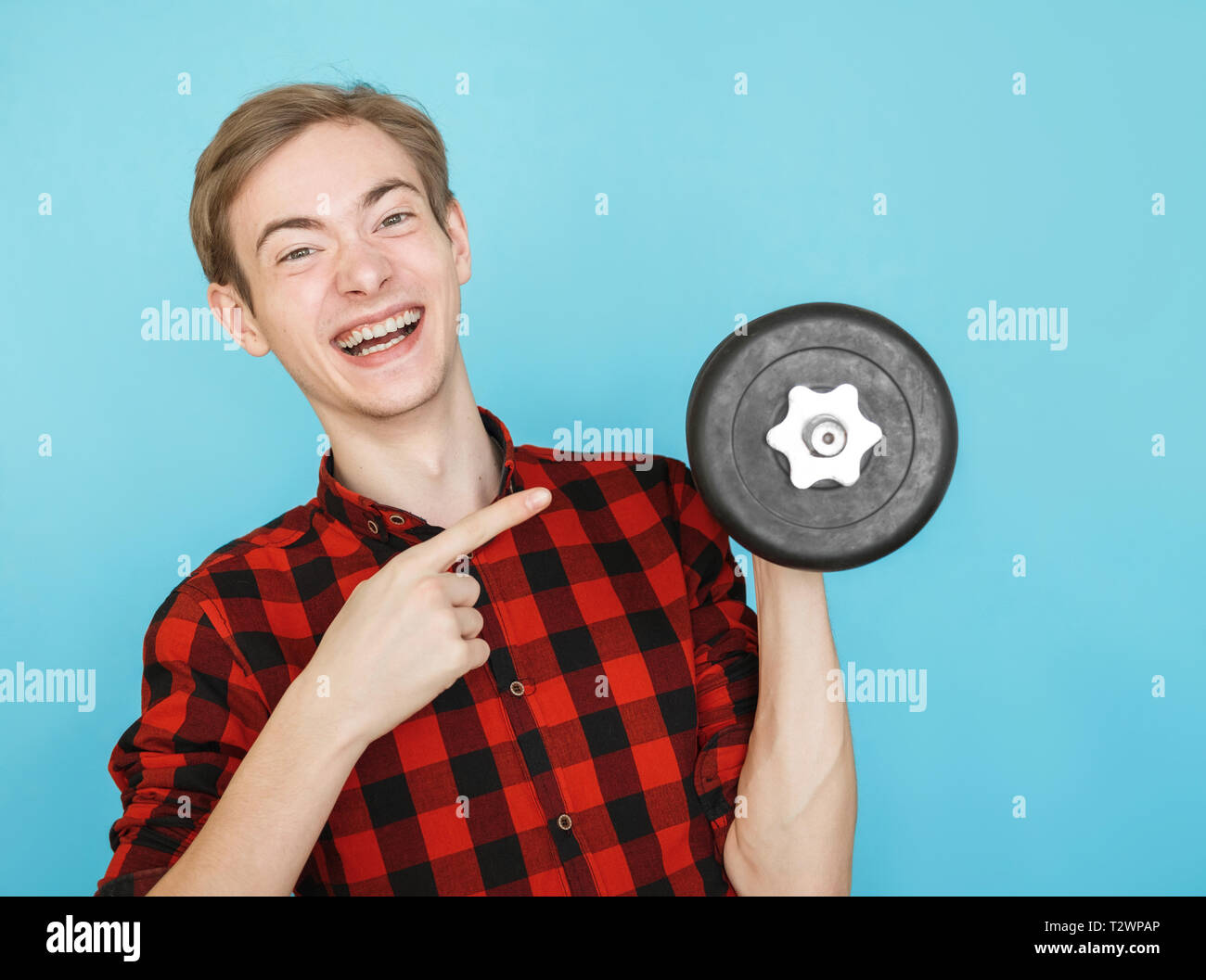 young smiling male teenager in red shirt on blue background points ...