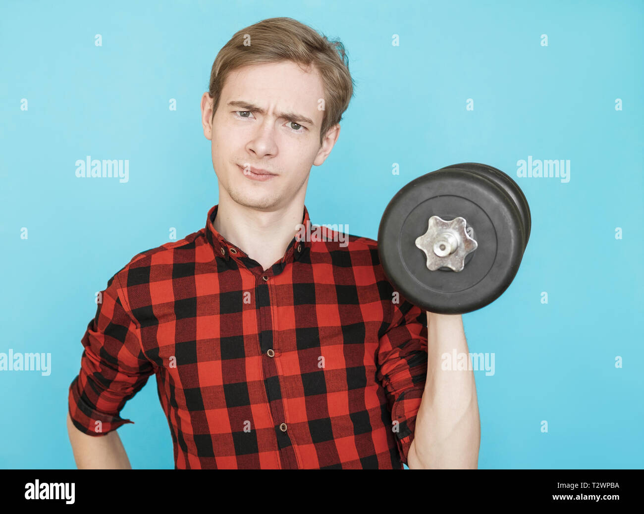 young smiling male teenager in red shirt on blue background points ...