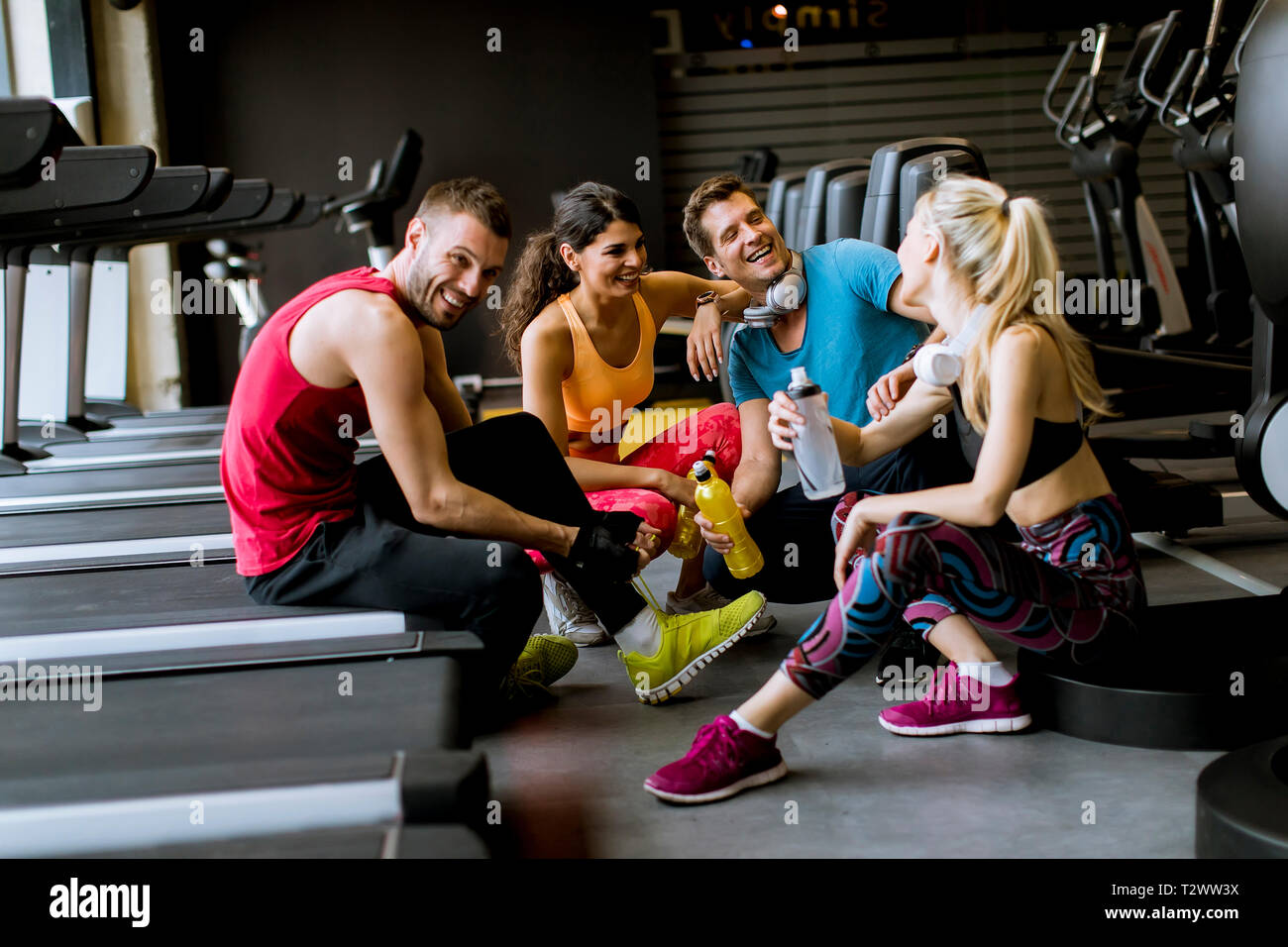Group pf young people in sportswear talking and laughing together while ...