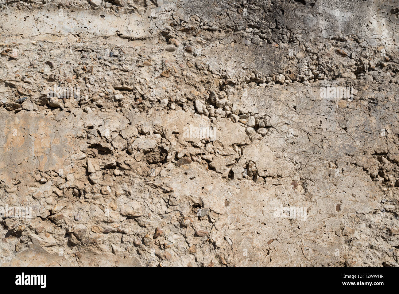 Rough textured concrete wall with protruding rubble for a background or ...