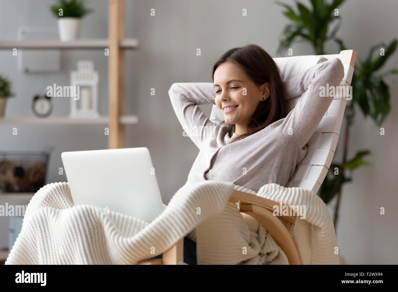 Woman resting on rocking chair on computer watching video online Stock ...