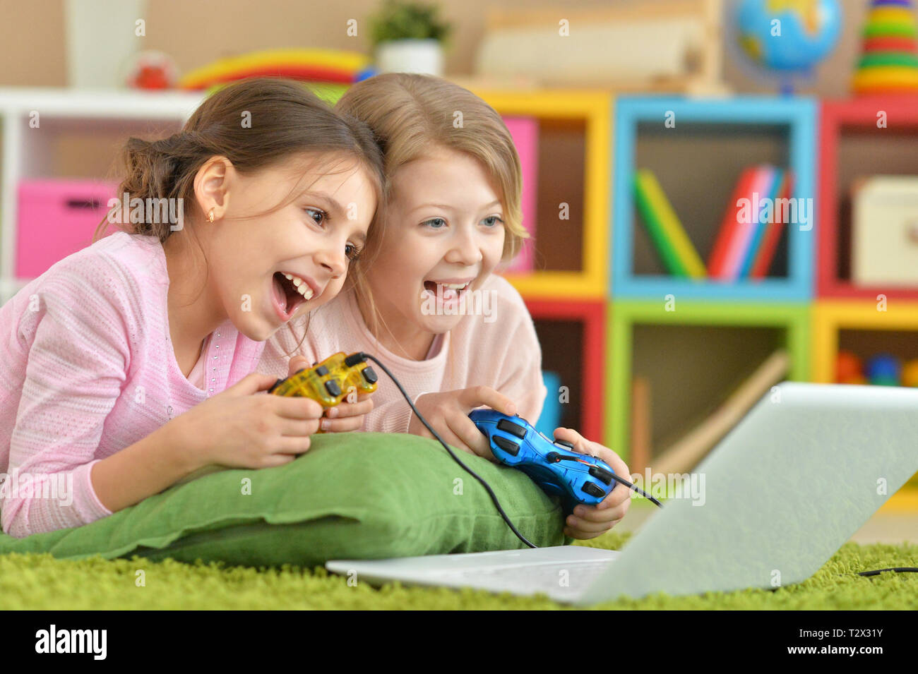 two cute little girls playing computer game on laptop together Stock ...