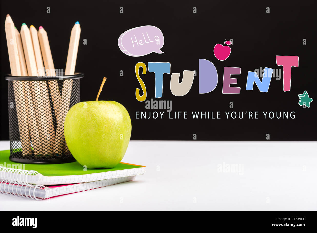fresh apple, notebooks and color pencils on table with enjoy life while ...